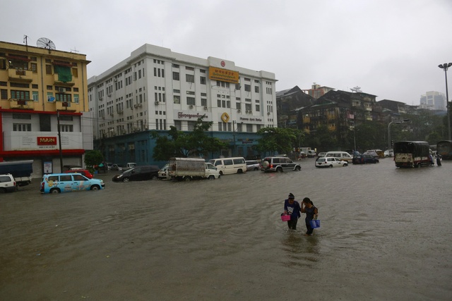 Girls walk along a flooded street during heavy rainfall in central ...